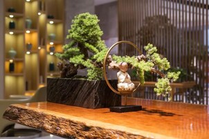 Uma mesa de madeira com uma árvore bonsai e uma figurina.