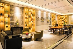 Um lobby de hotel moderno com área de estar, lareira e prateleiras decorativas na parede.