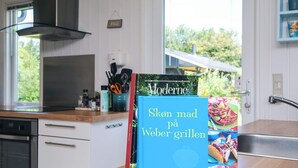 Uma cozinha com um livro intitulado 'Sken mad på Weber grillen' sobre o balcão.