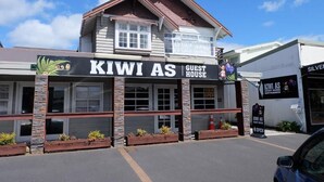 Um edifício de dois andares com uma placa que diz "KIWI AS GUEST HOUSE".