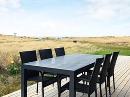 Varanda com mesa e cadeiras com vista para a praia.