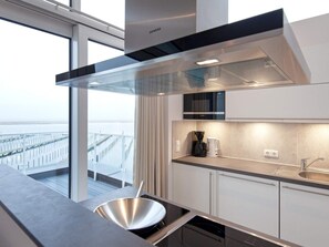 Cozinha moderna com exaustor de aço inoxidável, micro-ondas embutido e uma grande janela com vista para uma ponte.