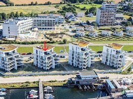 Uma área residencial moderna com edifícios altos, uma marina com barcos e um rio.