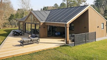 Uma casa moderna com um amplo deck, portas de vidro e área externa coberta.