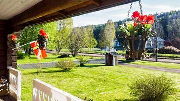 Uma área externa coberta com vista para uma paisagem verde, uma bandeira e um vaso de flores pendurado.