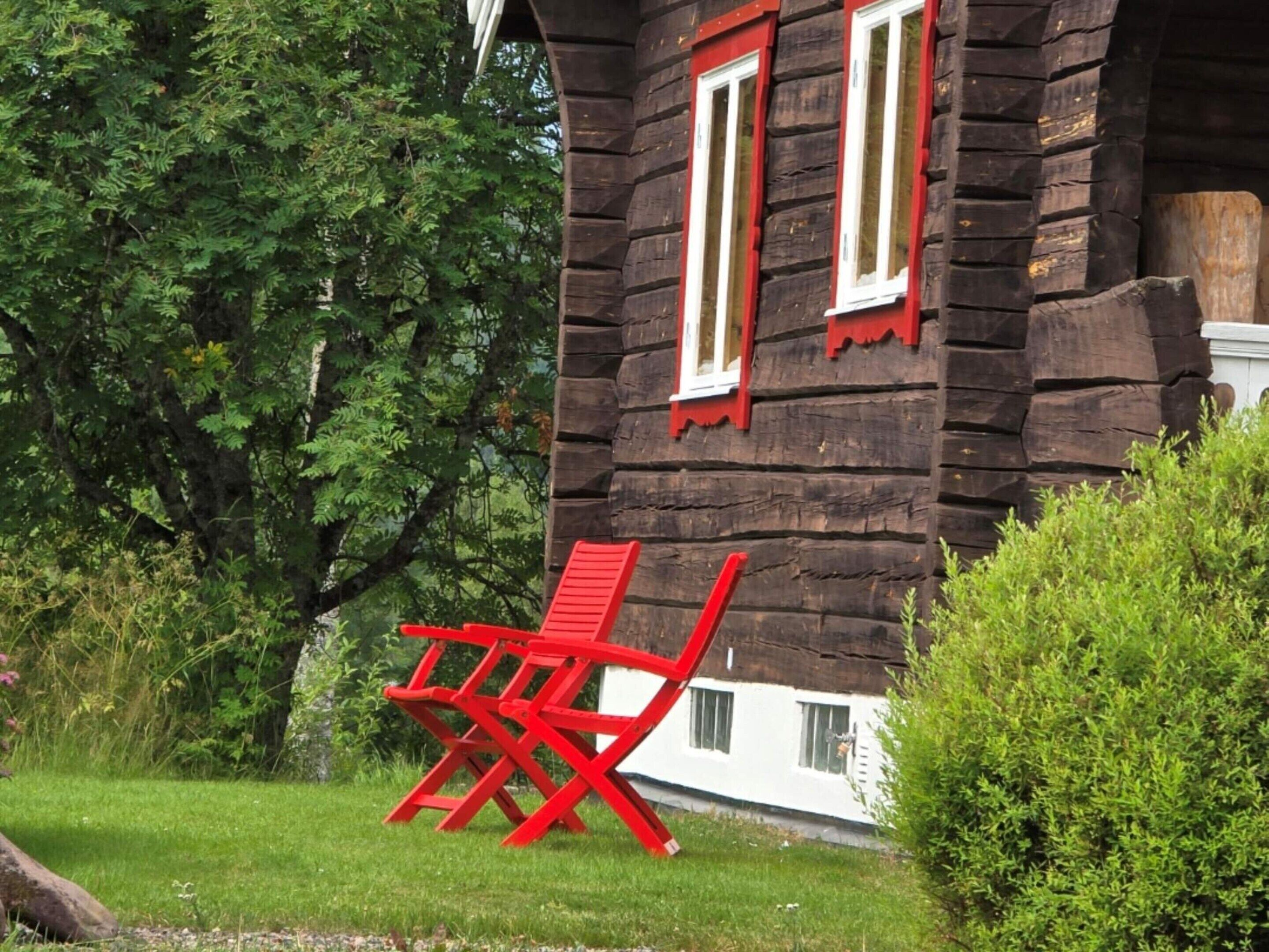Uma casa de madeira rústica com uma cadeira vermelha em frente.