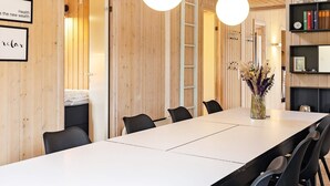 Um interior moderno com uma mesa de jantar comprida, cadeiras pretas, paredes de madeira e uma escada.
