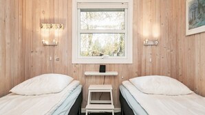 Quarto com duas camas, uma janela e uma estante com abajur.