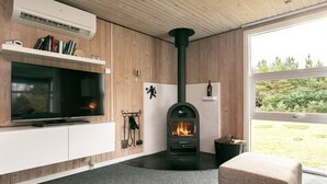 Uma sala de estar moderna com lareira, televisão e janela com vista para o verde.