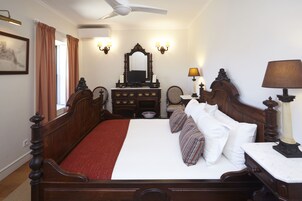 Um quarto com uma cama grande, cômoda, espelho e ventoinha no teto.