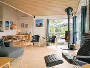 Uma sala de estar moderna com lareira, móveis de madeira e vista através de uma grande janela.