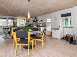 Cozinha moderna com área de refeições, cadeiras de madeira e luminária pendente.