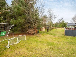 Quintal cercado com um gol de futebol, um casebre de madeira e uma área de estar coberta.