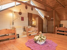 Um quarto aconchegante com móveis de madeira, uma mesa com um arranjo floral e um teto inclinado com janelas de claraboia.