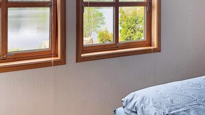 Quarto com uma cama, duas janelas e vista para um lago.