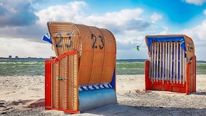 Duas cabanas de praia com os números 23 e 24, situadas numa praia arenosa com vista para o mar.