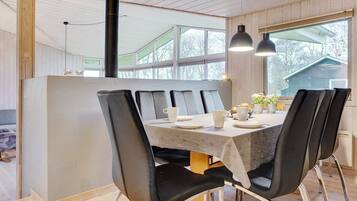 Espaço de jantar com mesa posta para quatro pessoas, rodeada por cadeiras pretas com pés de metal.