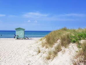 Uma praia com um posto salva-vidas azul claro e céu azul límpido.