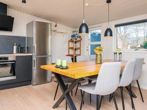 Cozinha moderna com mesa de jantar de madeira, cadeiras cinzas e iluminação pendente.