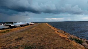 Uma área ribeirinha com gramado e barcos atracados.