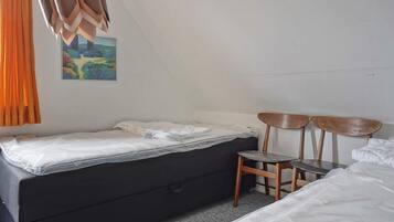 Quarto com uma cama, uma cadeira, uma escrivaninha e um quadro na parede.