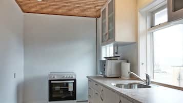 Cozinha compacta com forno embutido, pia e armários superiores.