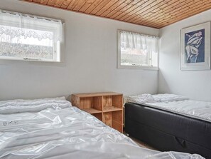 Quarto com duas camas, uma estante de madeira e um quadro na parede.