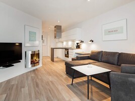 Uma sala de estar moderna com televisão de tela plana, lareira, sofá e mesa de centro.