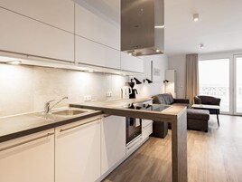Cozinha moderna com forno embutido, pia e área de refeições com sofá e mesa.