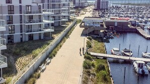Uma marina com barcos, uma passarela e edifícios modernos com varandas.