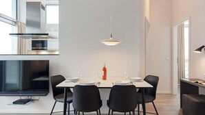 Uma área de refeições moderna com uma mesa retangular, seis cadeiras e uma luminária pendente.