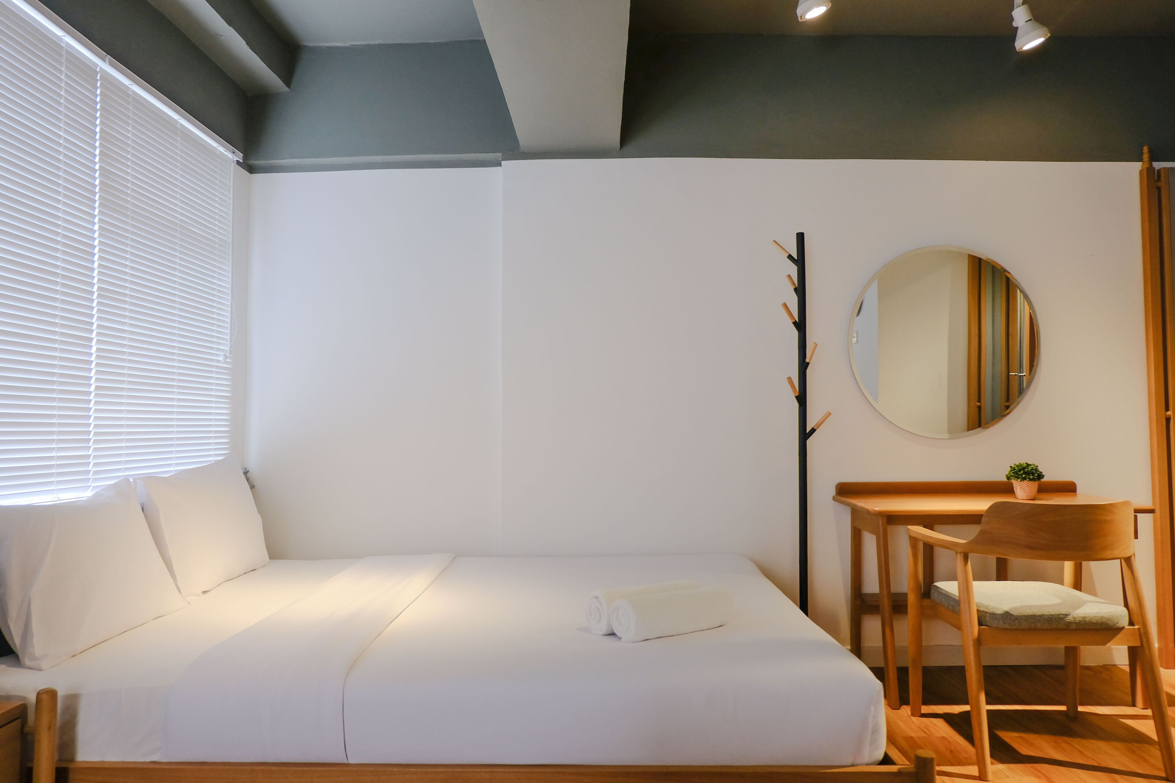 Um quarto bem arrumado com uma cama, uma escrivaninha e uma cadeira.