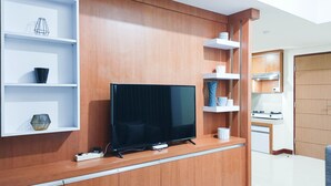 Uma sala de estar moderna com uma TV de tela plana, armários de madeira e prateleiras embutidas com objetos decorativos.
