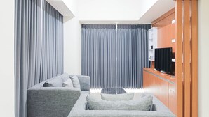 Uma sala de estar moderna com um conjunto de sofá, uma televisão de tela plana e um armário de madeira.