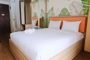 Cama bem arrumada com lençóis brancos e cabeceira laranja, piso de madeira e parede com padrão de folhagem tropical.