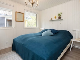 Quarto com cama, lustre, janela e prateleira com uma planta.