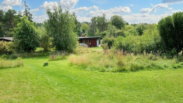 Um campo gramado com um edifício vermelho, cercado por árvores e vegetação.