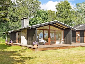 Uma casa moderna com um deck espaçoso, chaminé e varanda envidraçada.