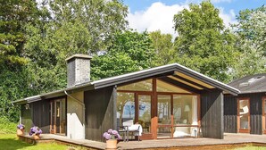 Uma casa moderna com um deck espaçoso, chaminé e varanda envidraçada.
