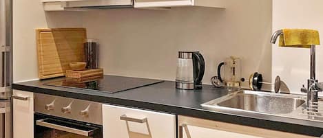 Uma cozinha equipada com fogão, forno, pia e diversos utensílios.