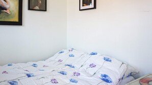 Quarto com cama, travesseiro, mesa de cabeceira e duas fotos emolduradas na parede.