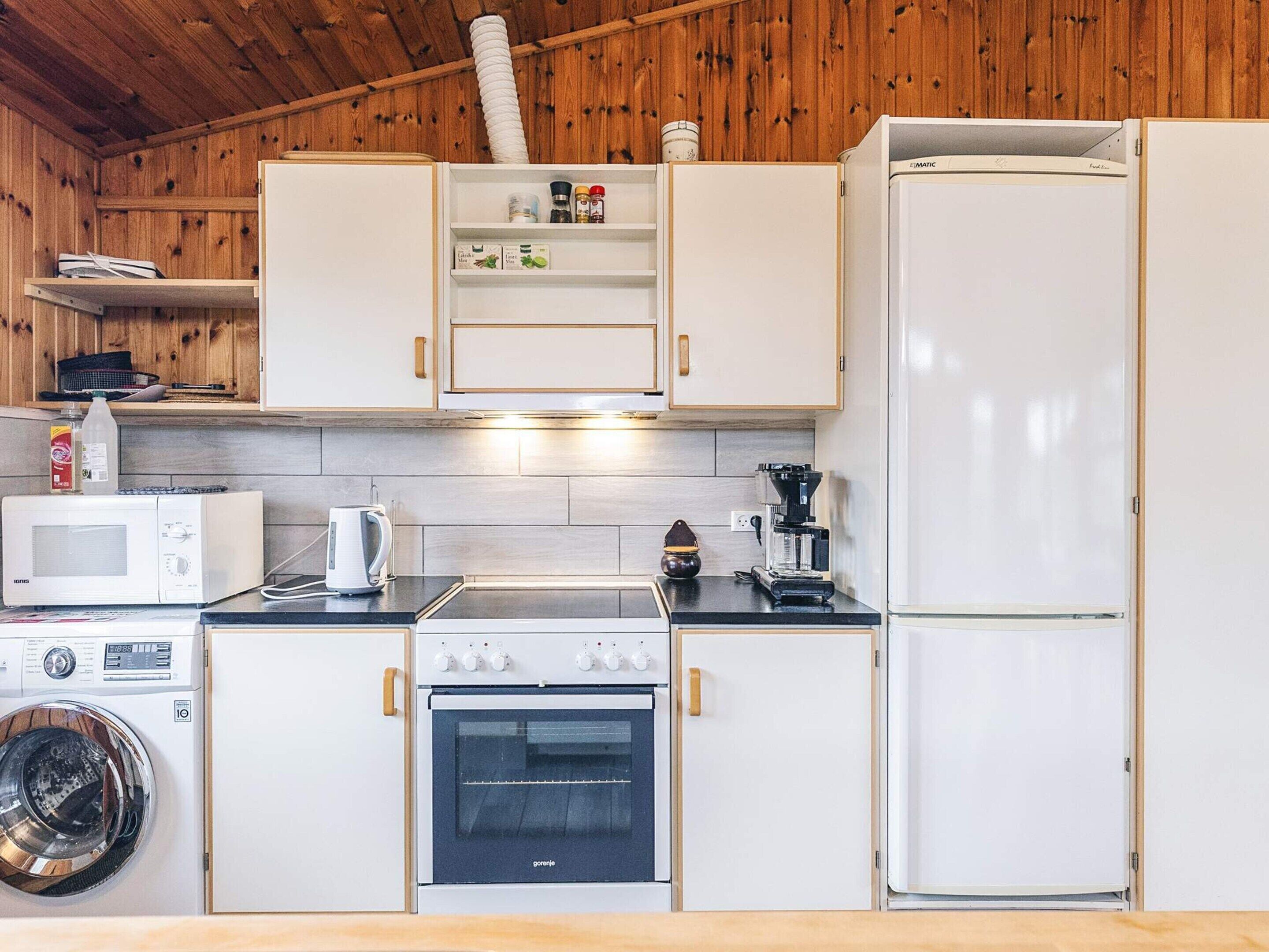 Cozinha compacta equipada com micro-ondas, chaleira, máquina de café, forno e máquina de lavar.