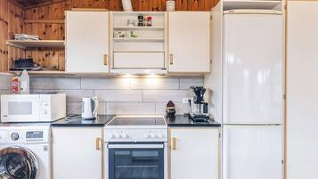 Cozinha compacta equipada com micro-ondas, chaleira, máquina de café, forno e máquina de lavar.