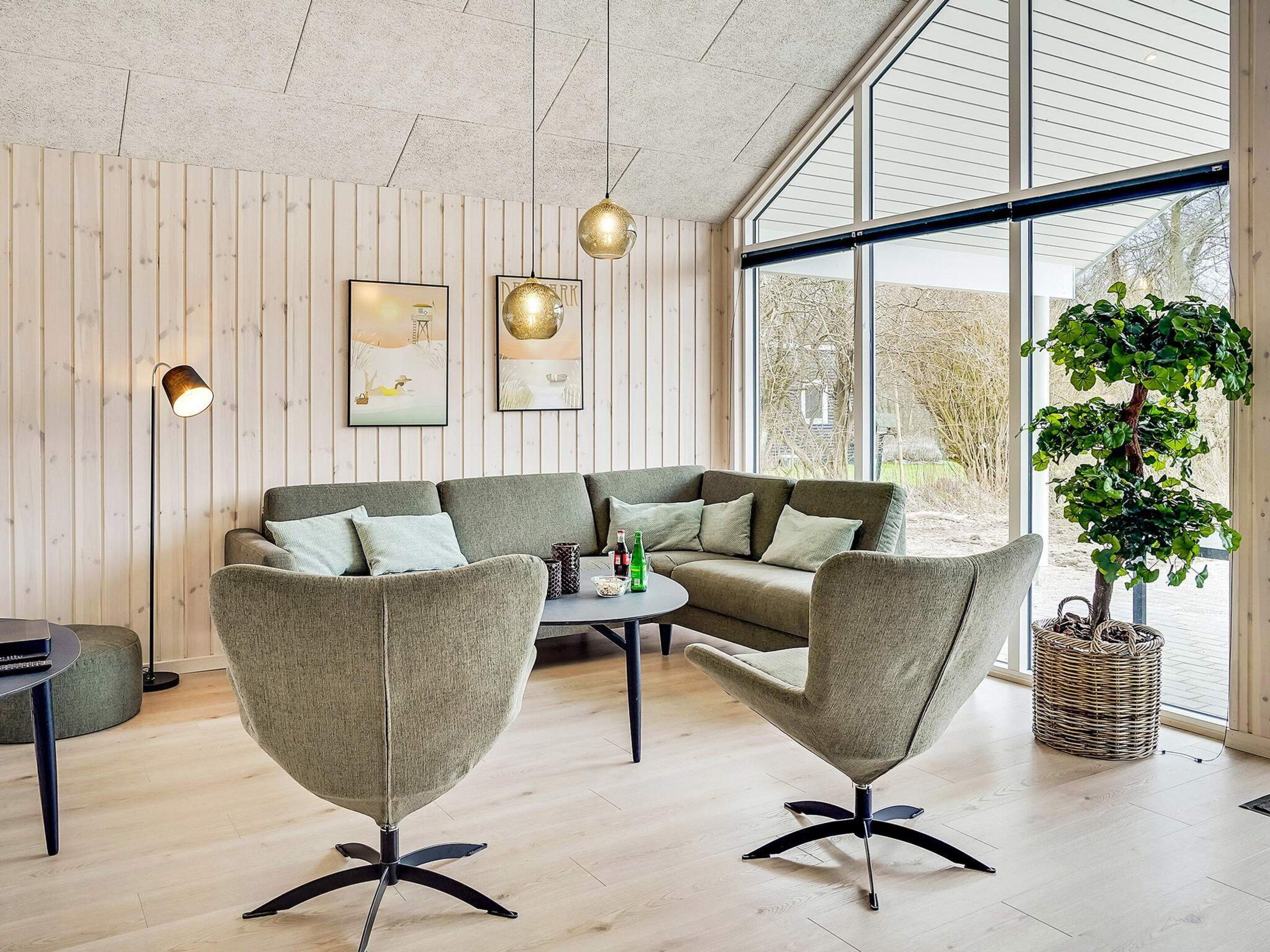 Uma sala de estar moderna com um sofá seccional, duas poltronas, uma mesa de centro e uma grande janela com vista para o exterior.