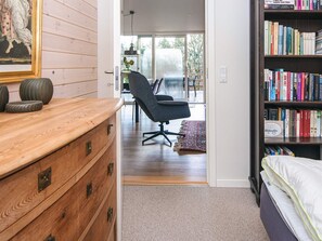 Um quarto com penteadeira de madeira, uma estante e uma cadeira.