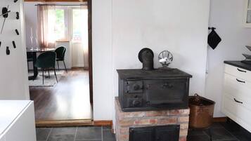 Uma cozinha com fogão de tijolos, área de jantar com cadeiras, e vista por um arco.