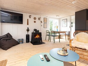 Uma sala de estar aconchegante com lareira, televisão e um espaço de jantar com cadeiras e mesa.