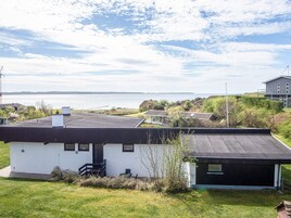 Uma casa moderna com telhado plano, um pequeno alpendre e vista para o mar.
