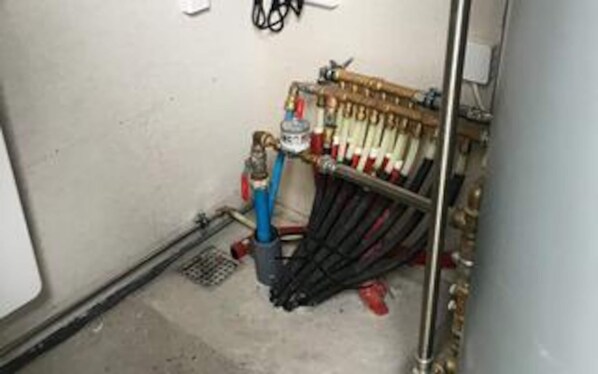 Um espaço de serviço com um aquecedor de água, um radiador e um sistema de ventilação.