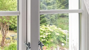 Janela com vista para um jardim, incluindo uma árvore e uma mesa.